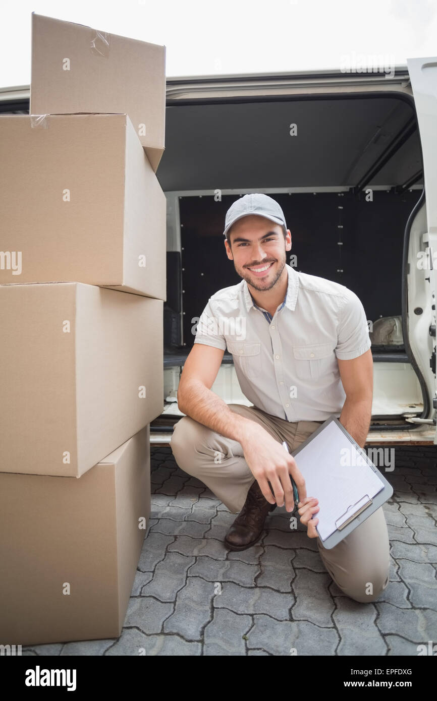Delivery driver smiling at camera with pile of packages Stock Photo - Alamy