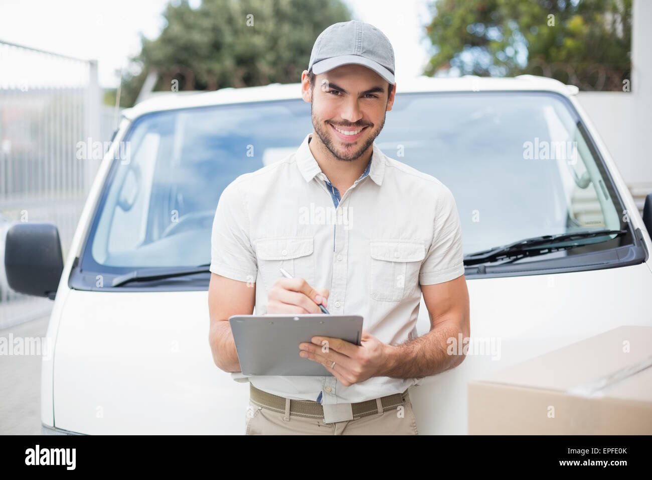 Delivery driver smiling at camera by his van Stock Photo - Alamy