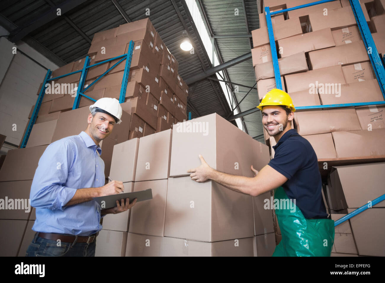 Warehouse worker loading up a pallet with manager Stock Photo - Alamy