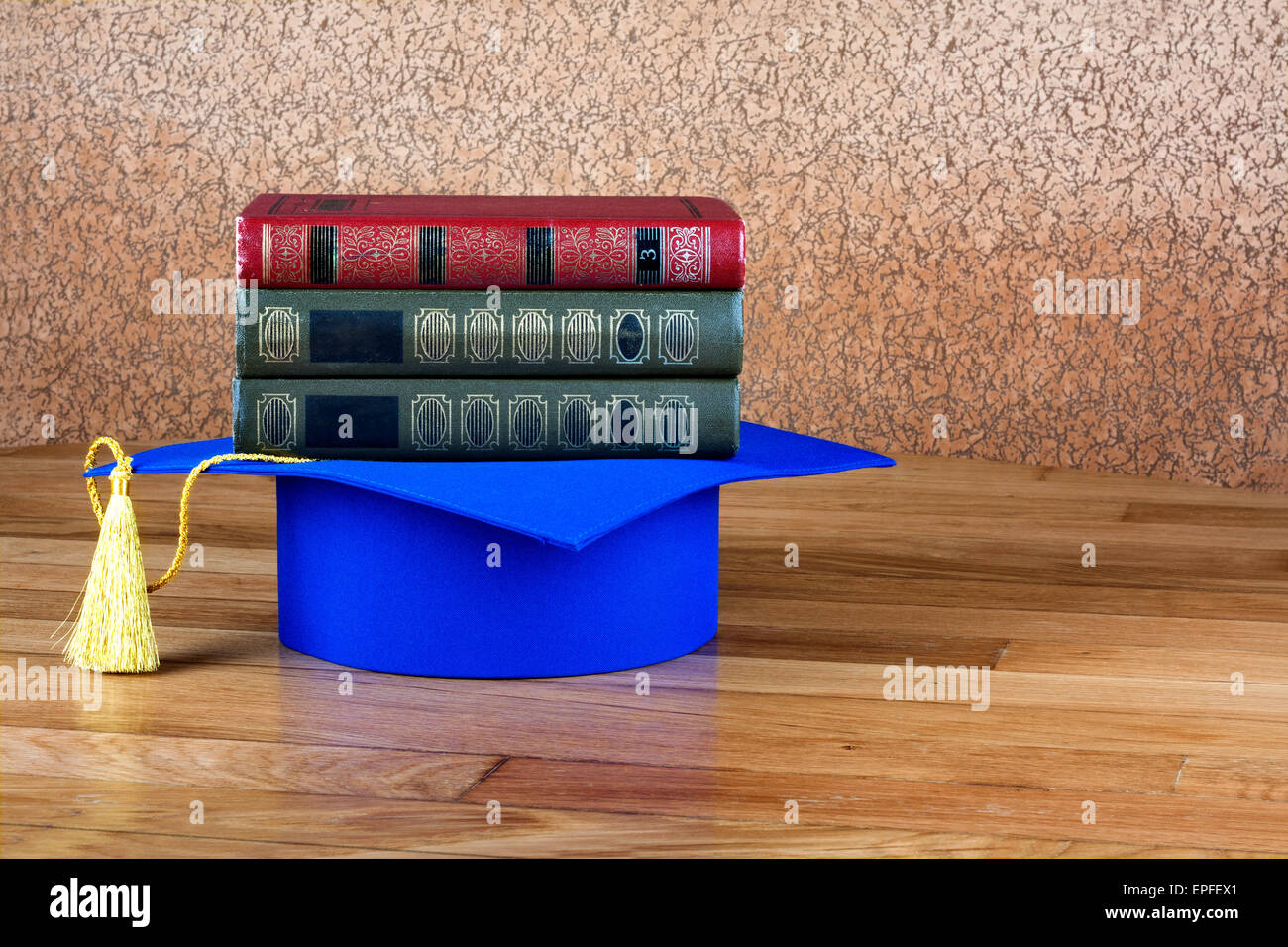 Graduation mortarboard on top of stack of books on abstract background ...
