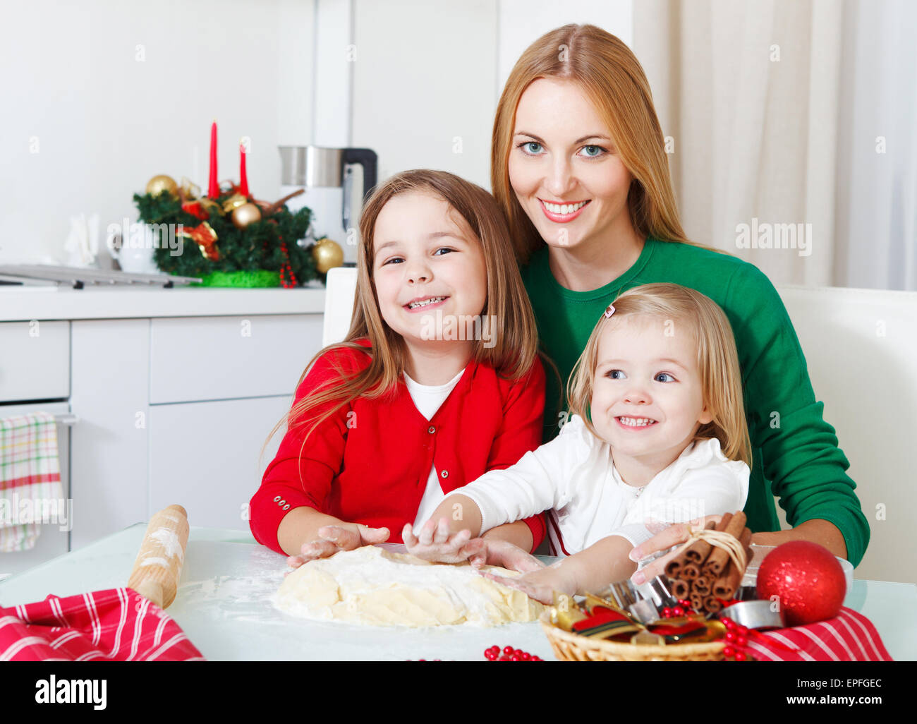 Two adorable girls with mother baking Christmas cookies in the kitchen ...