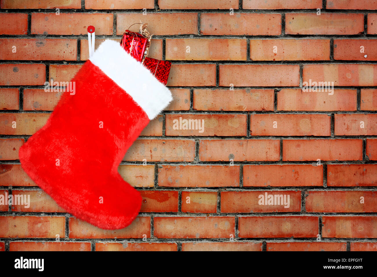 Red christmas boot with gifts on background brick wall Stock Photo - Alamy