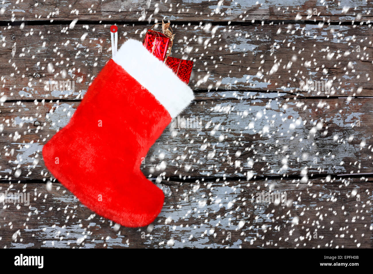 Red christmas boot with gifts on background wooden wall Stock Photo - Alamy