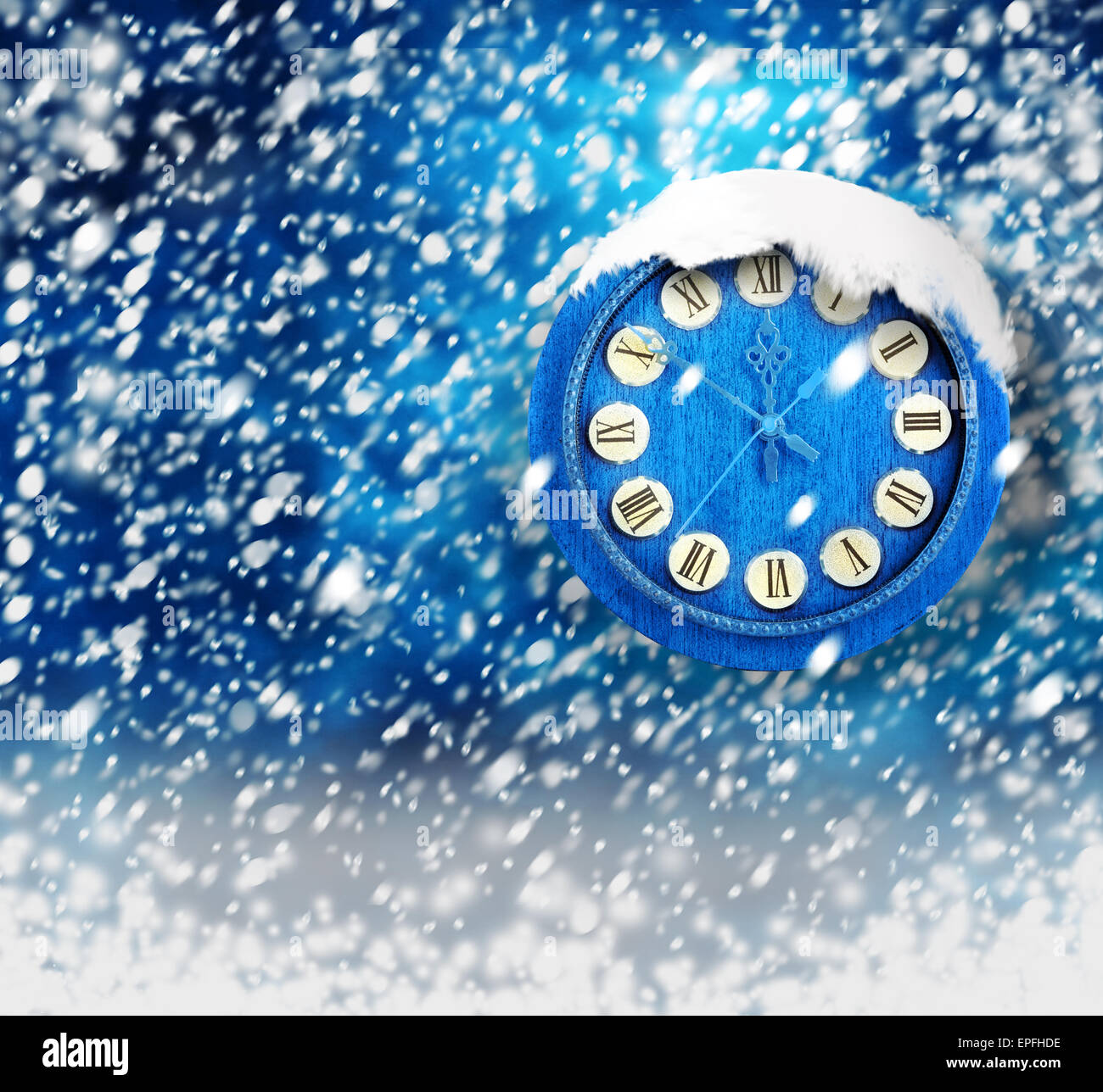 Snow-covered clock on abstract blue background Stock Photo - Alamy