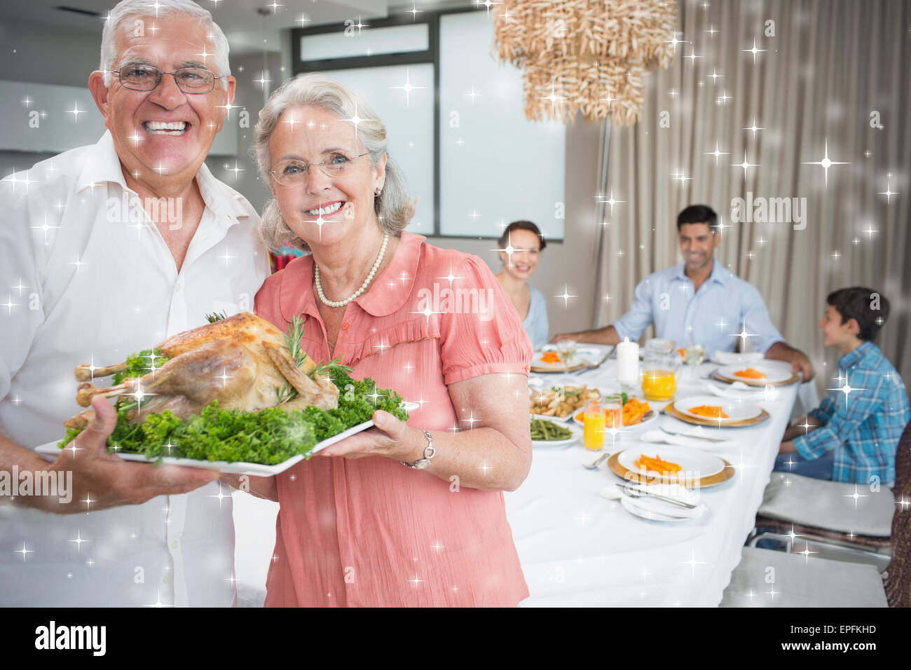 Composite image of grandparents holding chicken roast with family at ...