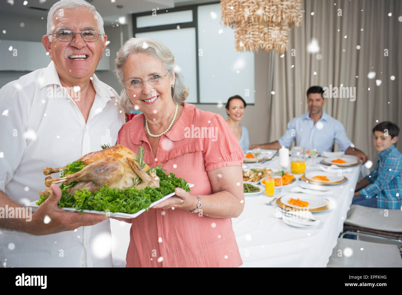Composite image of grandparents holding chicken roast with family at ...