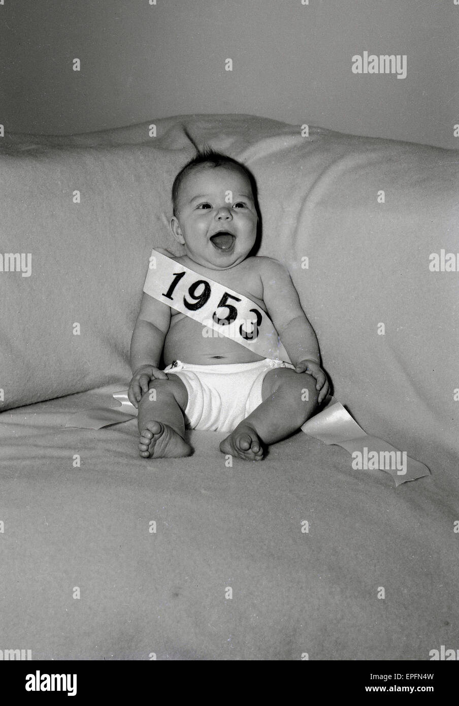 1953, historical, a baby with a 1953 year banner, sits on a sofa Stock ...