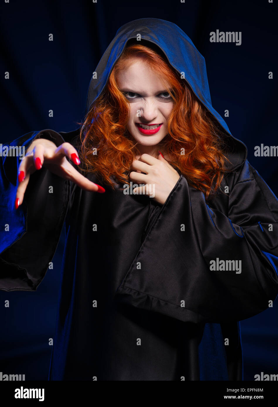 Young witch on blue light background Stock Photo - Alamy