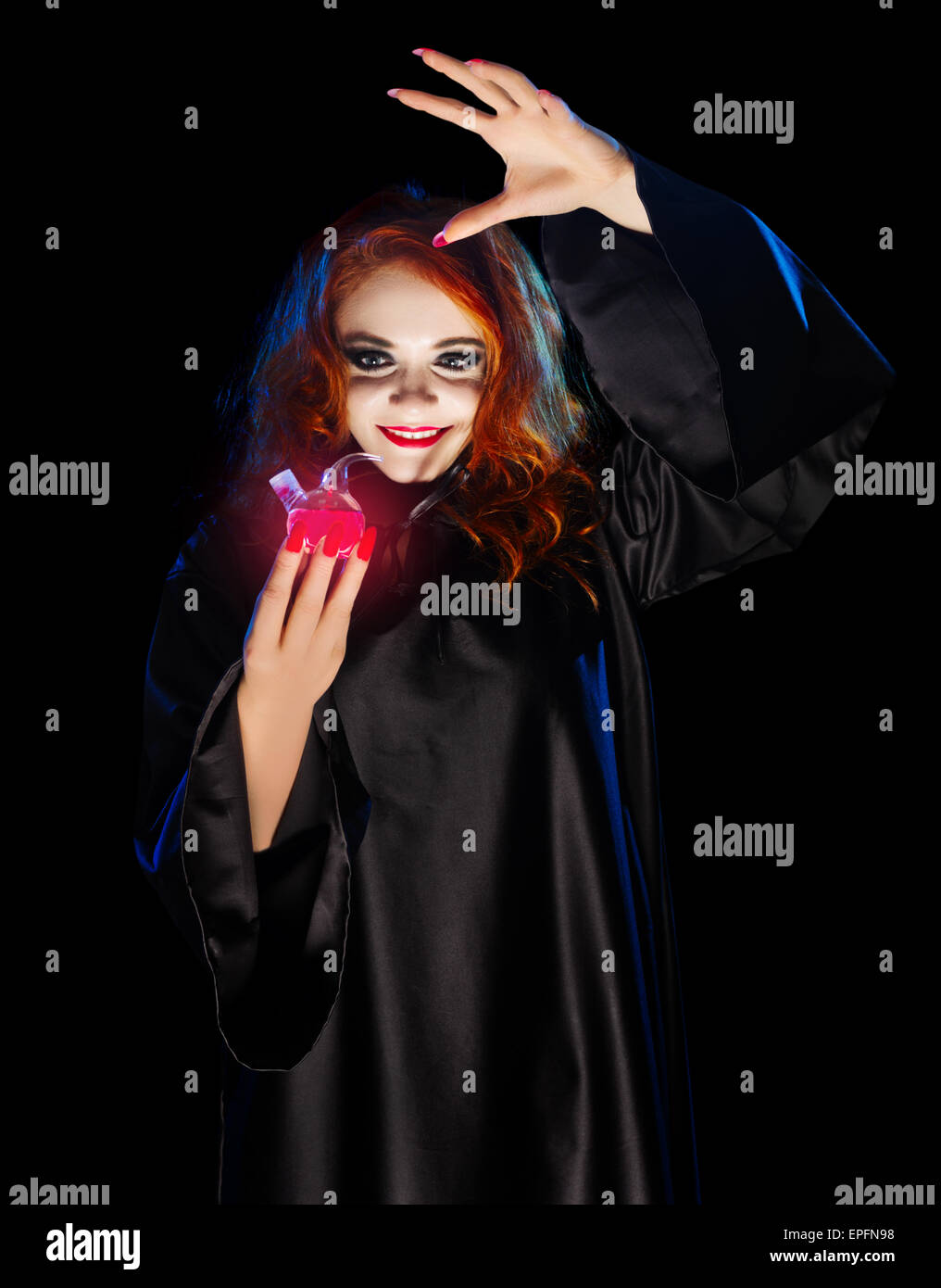 Young witch with red potion isolated Stock Photo - Alamy
