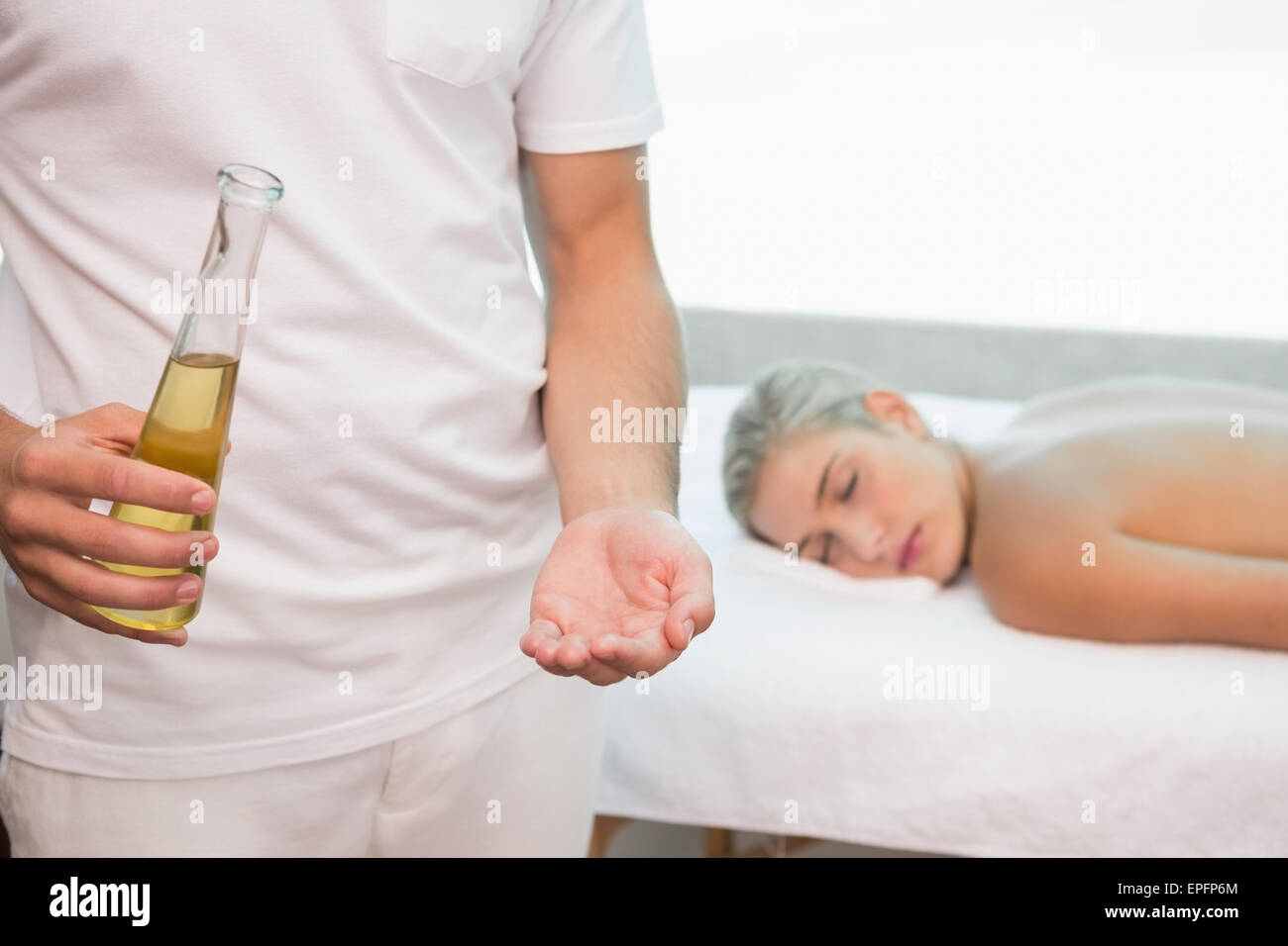 Masseur holding oil with woman lying background at spa center Stock ...