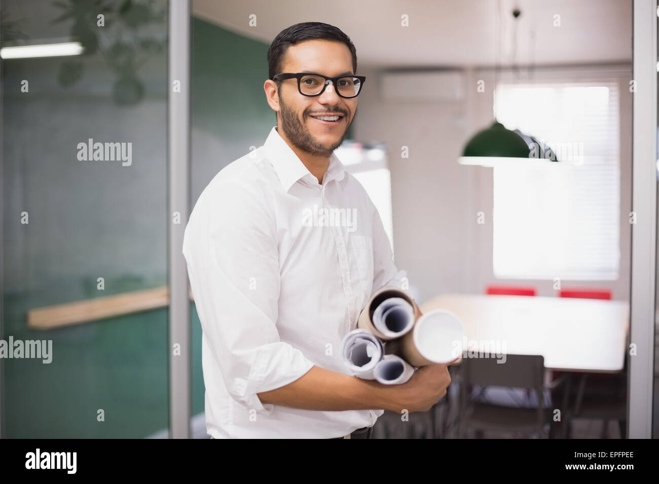 Casual architect smiling at camera holding blueprints Stock Photo - Alamy
