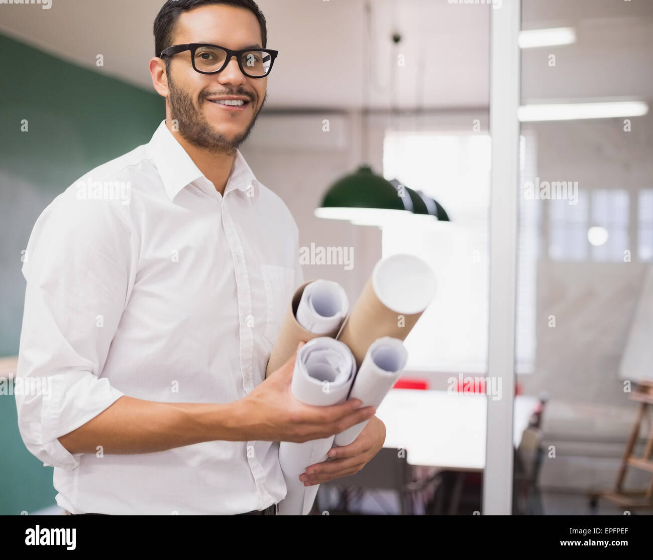 Casual architect smiling at camera holding blueprints Stock Photo - Alamy