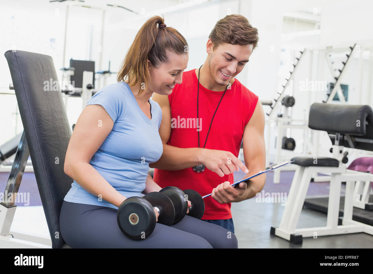 Personal trainer working with client holding dumbbell Stock Photo - Alamy