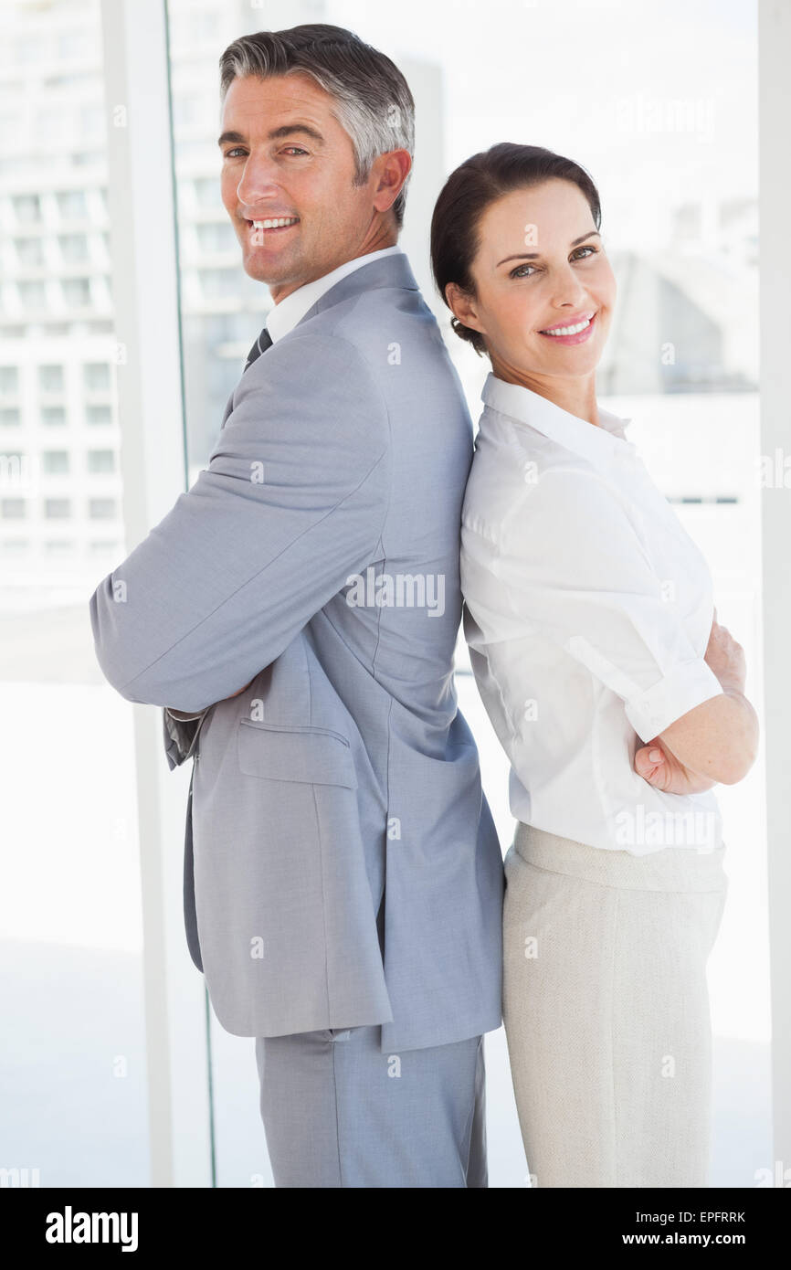 Happy employees standing back to back Stock Photo - Alamy