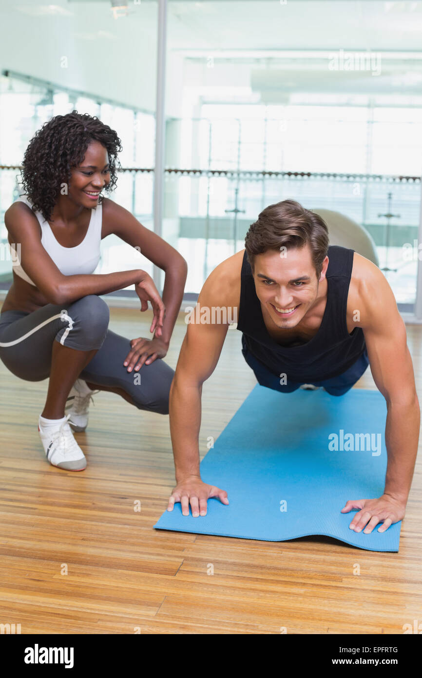 Personal trainer working with client on exercise mat Stock Photo - Alamy
