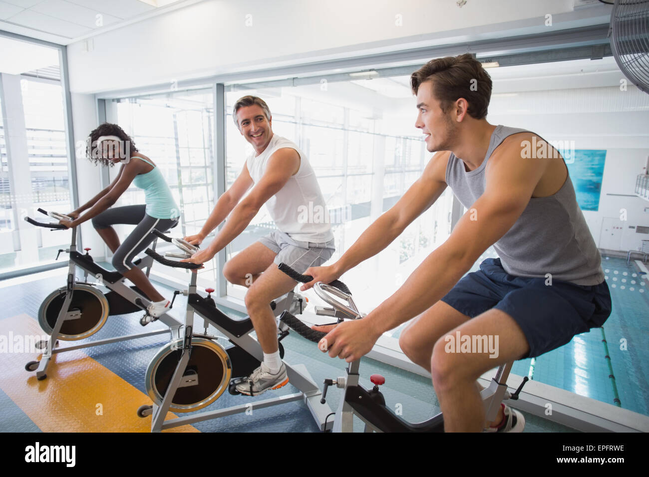 Three fit people working out on exercise bikes Stock Photo - Alamy