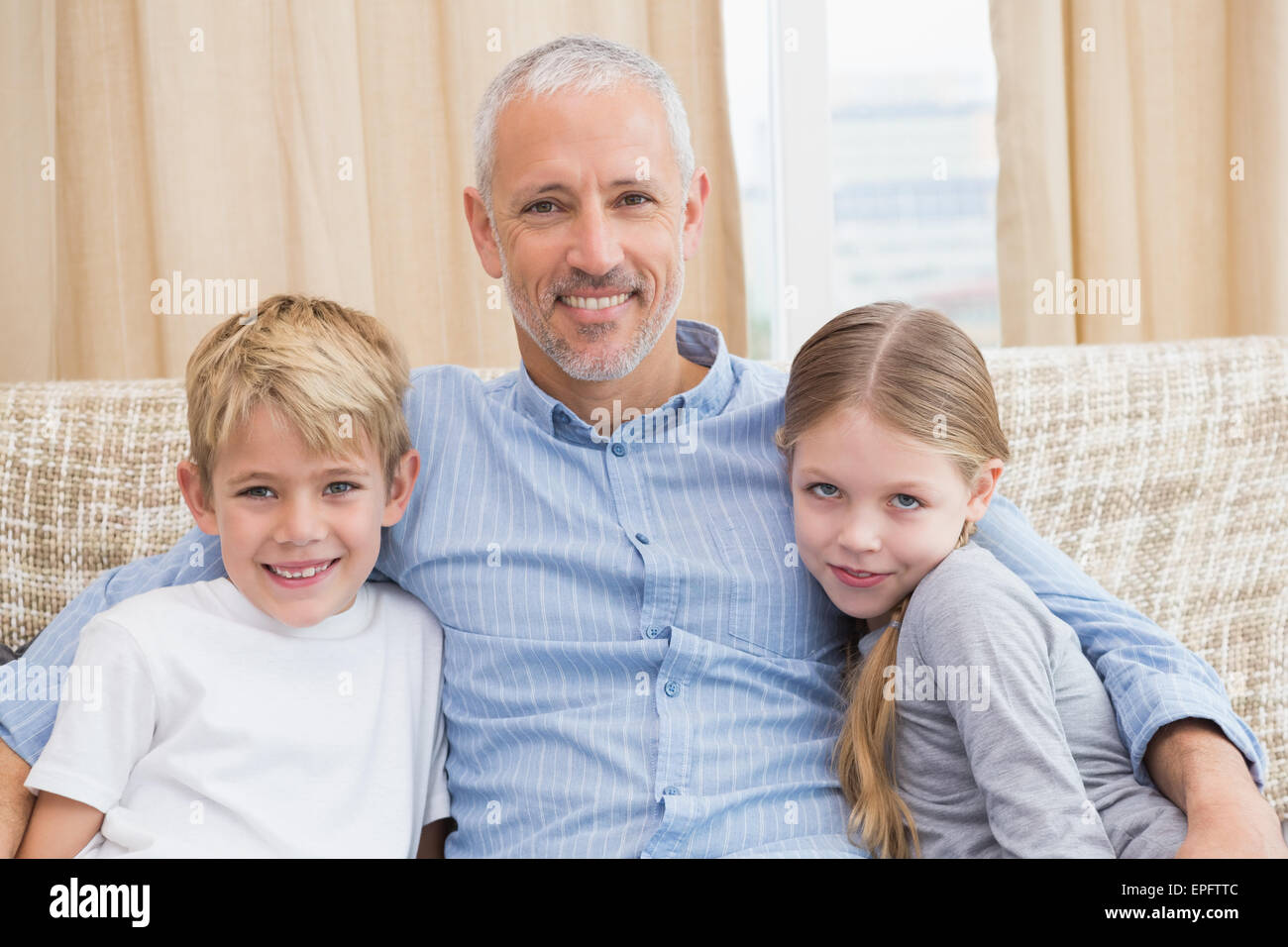 Father smiling at camera with his children on sofa Stock Photo - Alamy