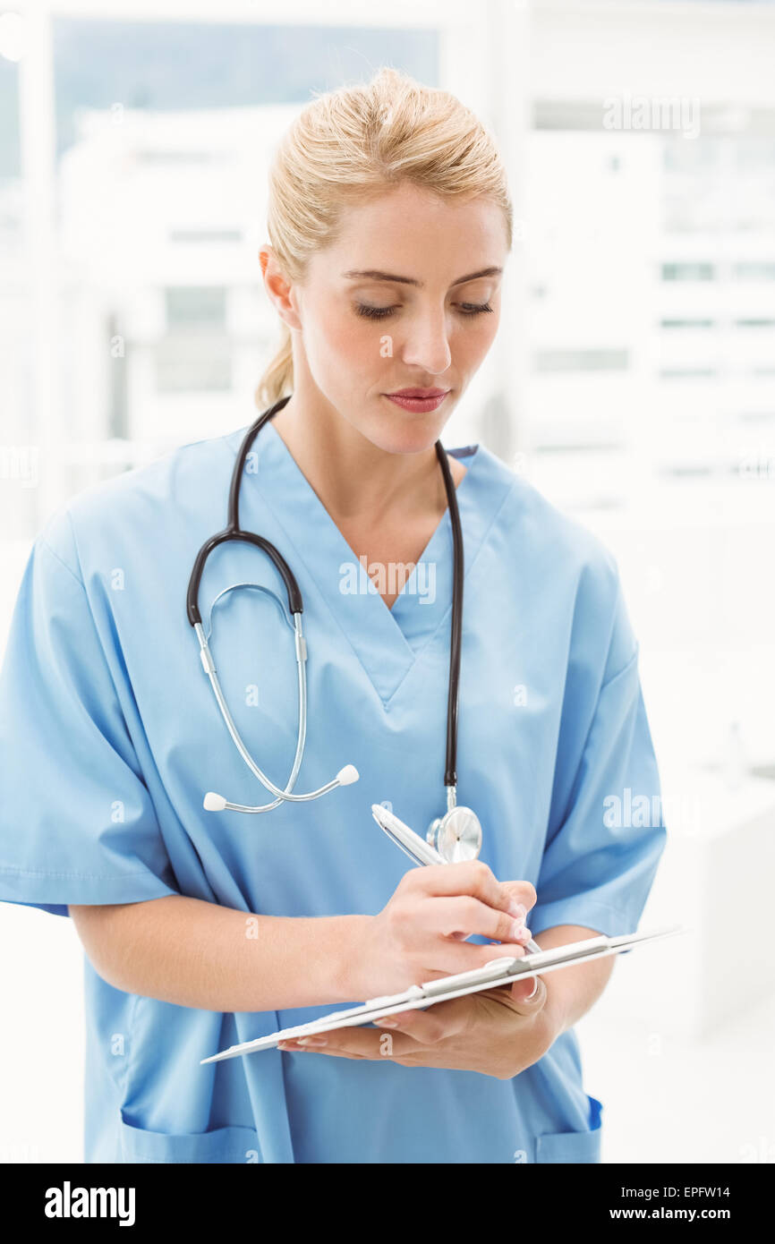Concentrated female doctor writing on clipboard Stock Photo - Alamy