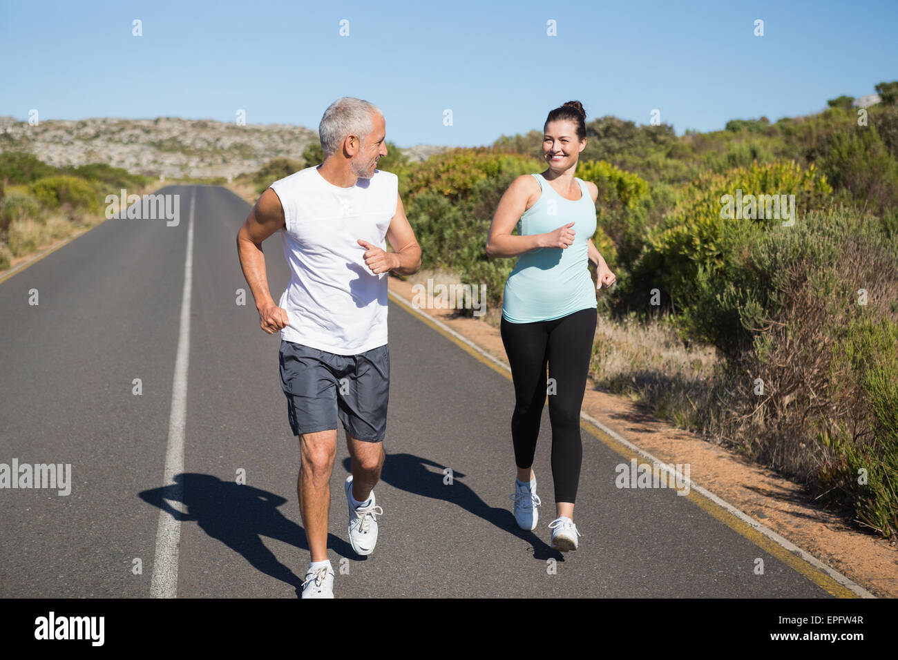 Fit couple running on the open road together Stock Photo - Alamy