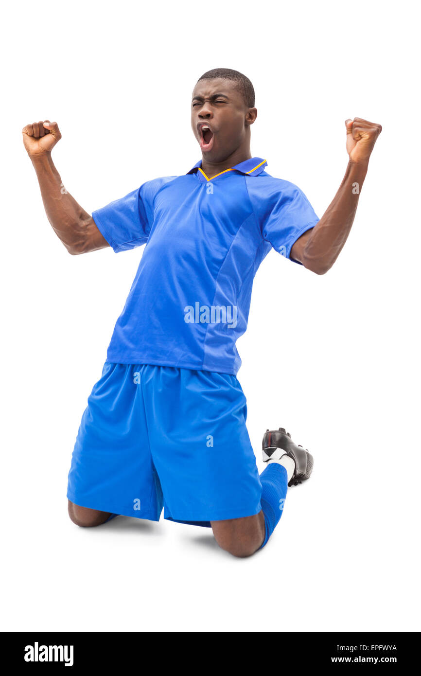 Excited football player in blue cheering on his knees Stock Photo - Alamy
