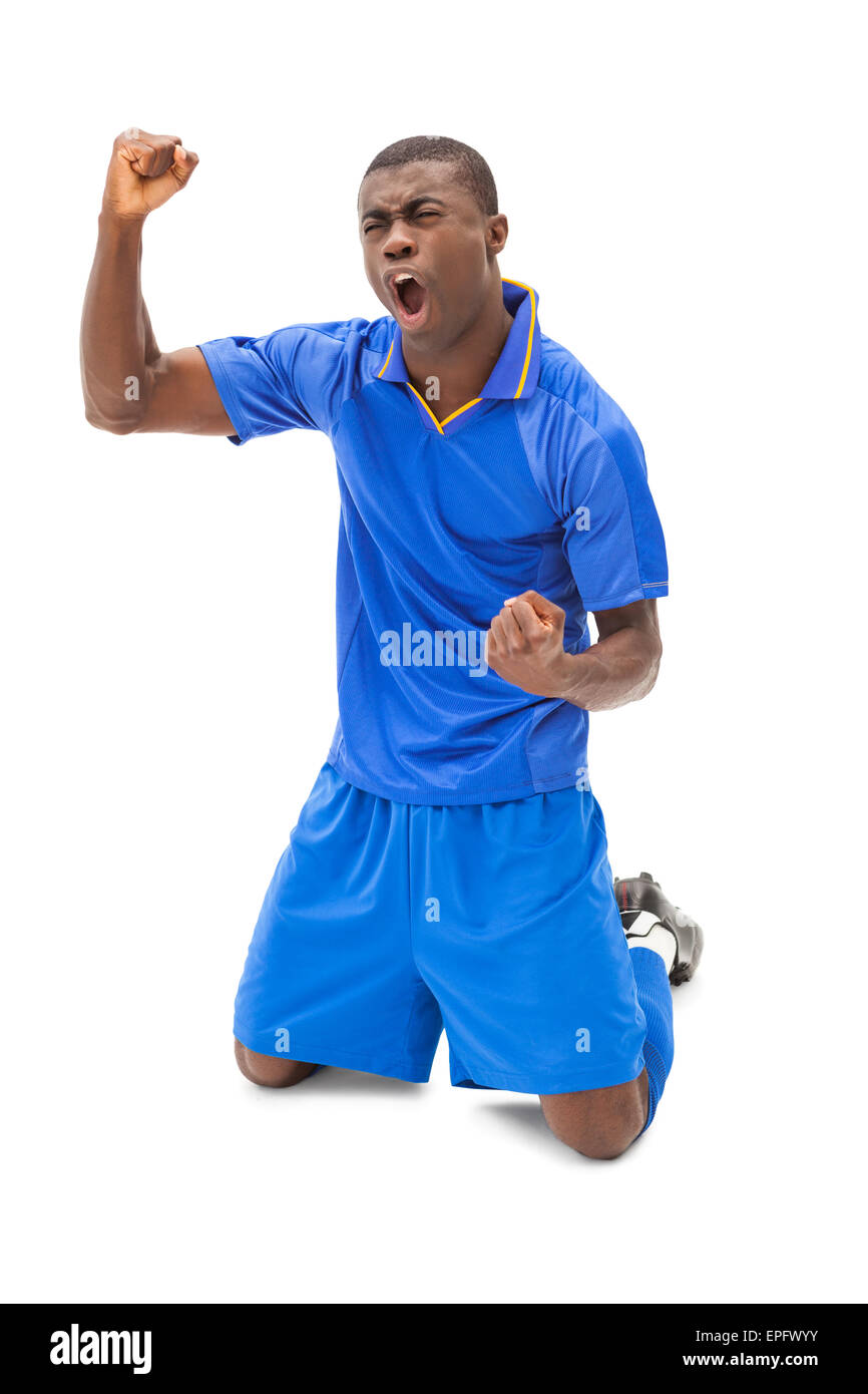 Excited football player in blue cheering on his knees Stock Photo - Alamy
