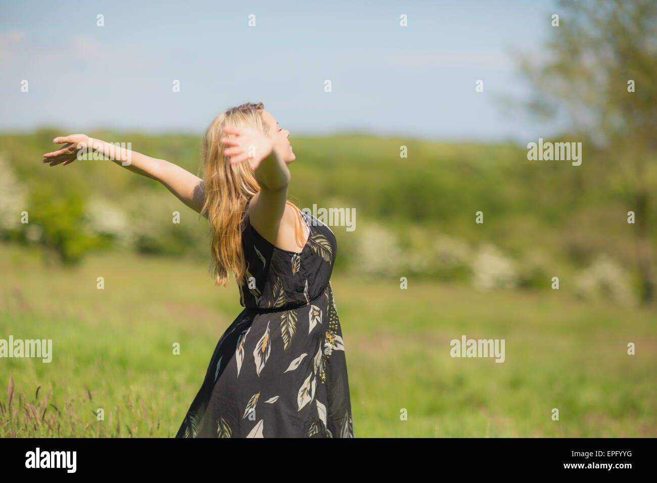 Pretty blonde in sundress standing with arms out Stock Photo - Alamy