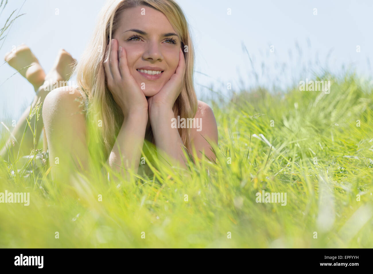 Pretty blonde in sundress lying on grass smiling Stock Photo - Alamy