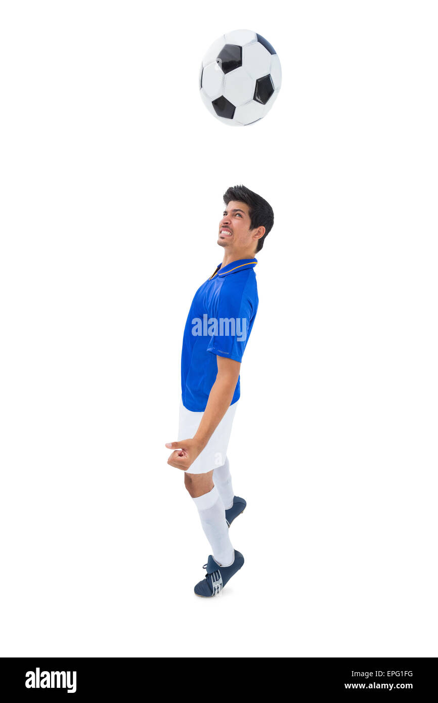 Football player in blue heading ball Stock Photo - Alamy