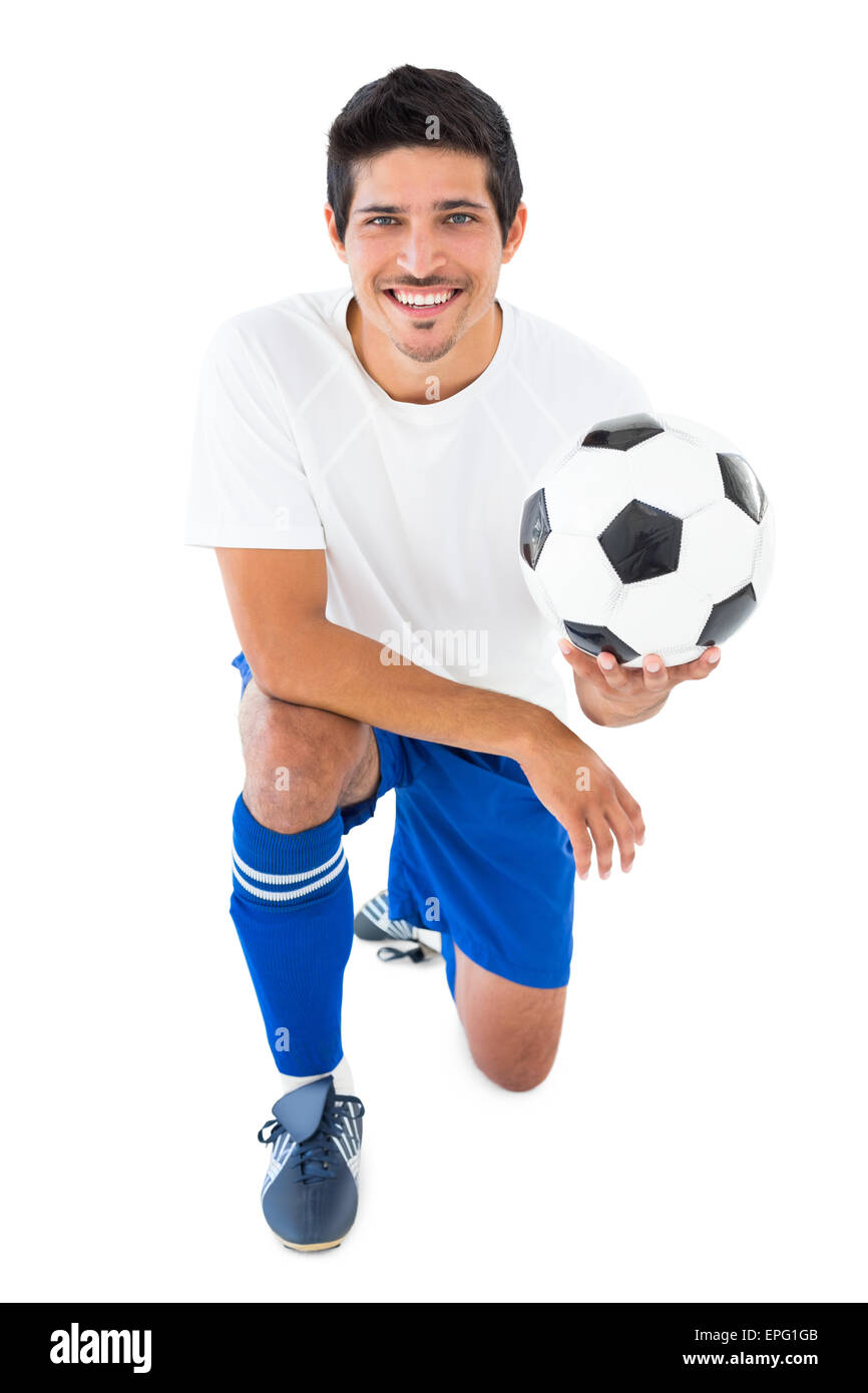 Football player in blue kneeling with ball Stock Photo - Alamy