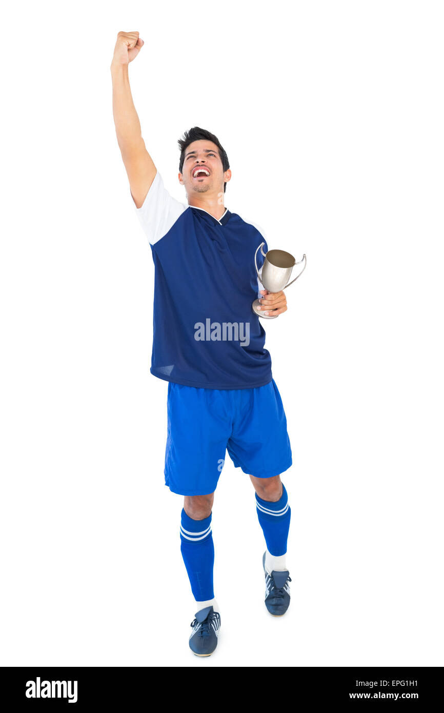 Football player in blue holding winners cup Stock Photo - Alamy