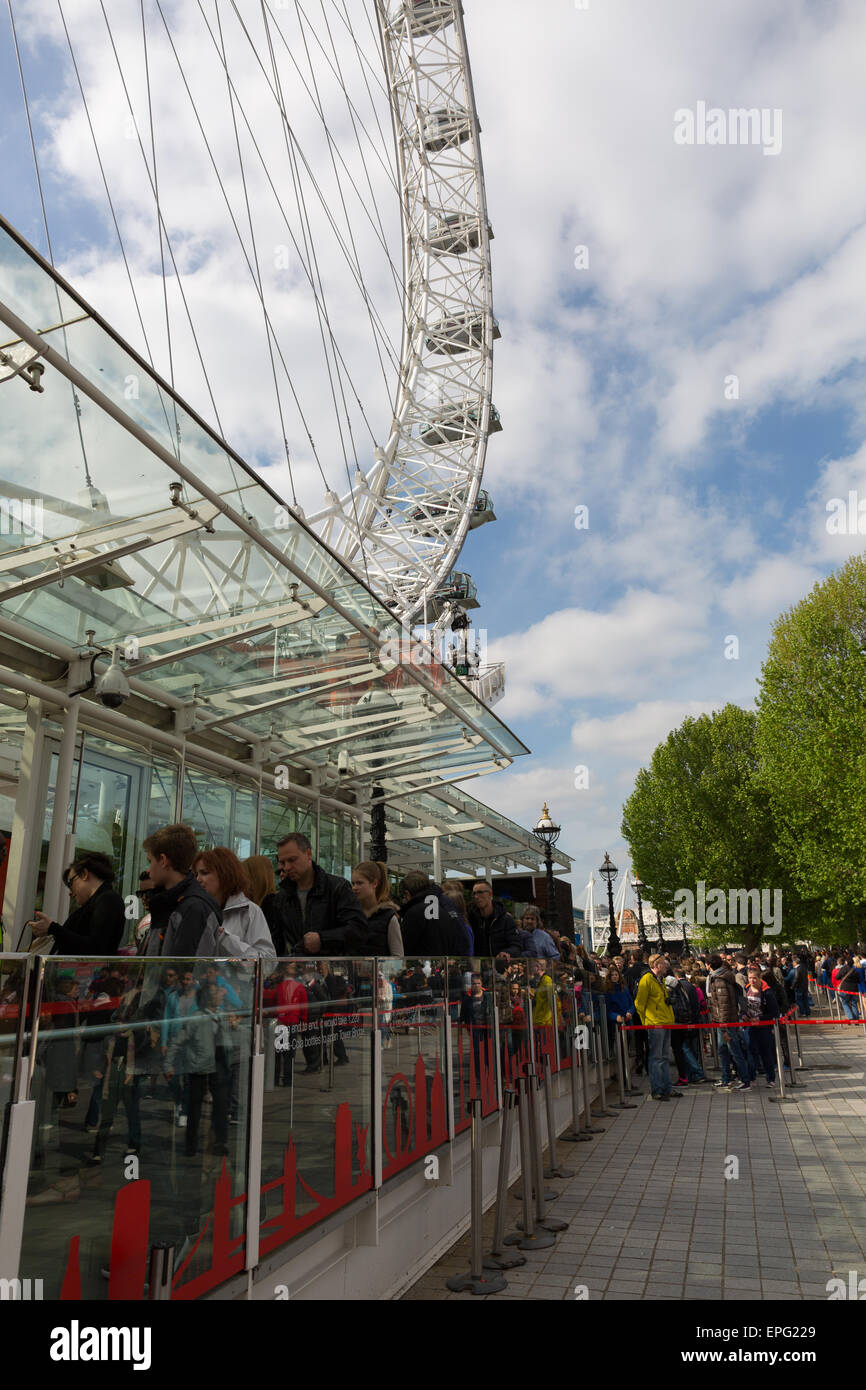 A queue of tourists waiting at the London Eye sponsored by Coca Cola ...