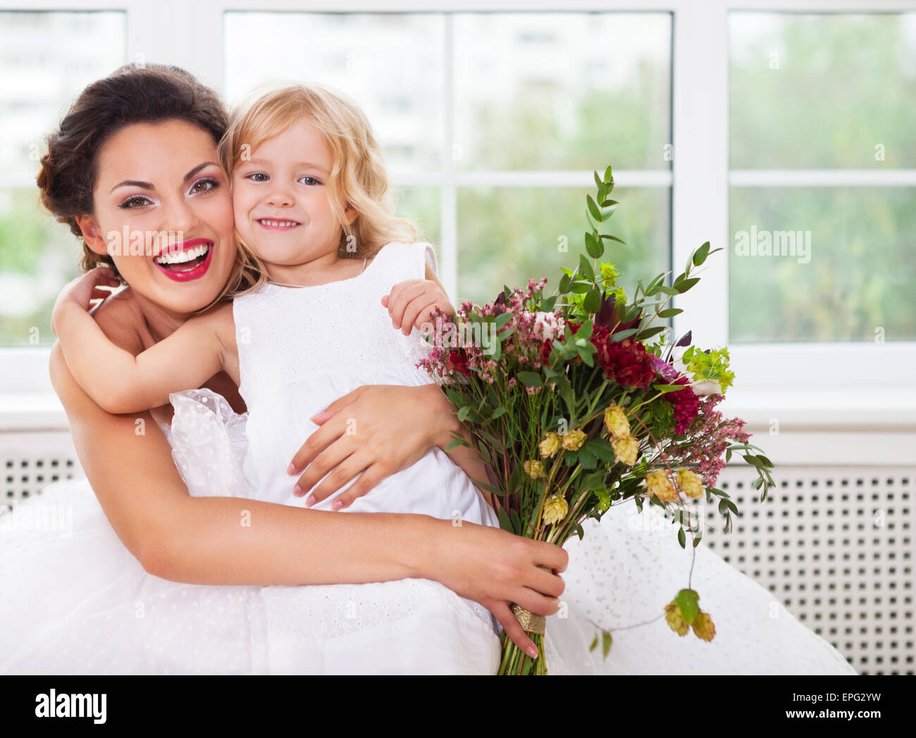 Smiling happy bride and a flower girl indoors Stock Photo - Alamy