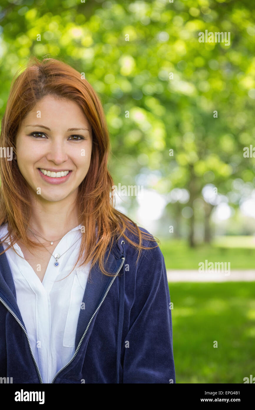Pretty redhead smiling at camera in the park Stock Photo - Alamy