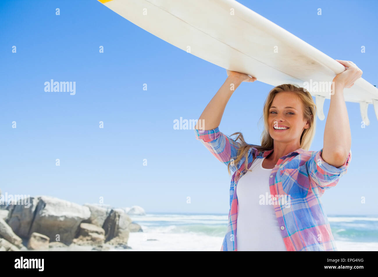 Blonde surfer holding her board smiling at camera Stock Photo - Alamy