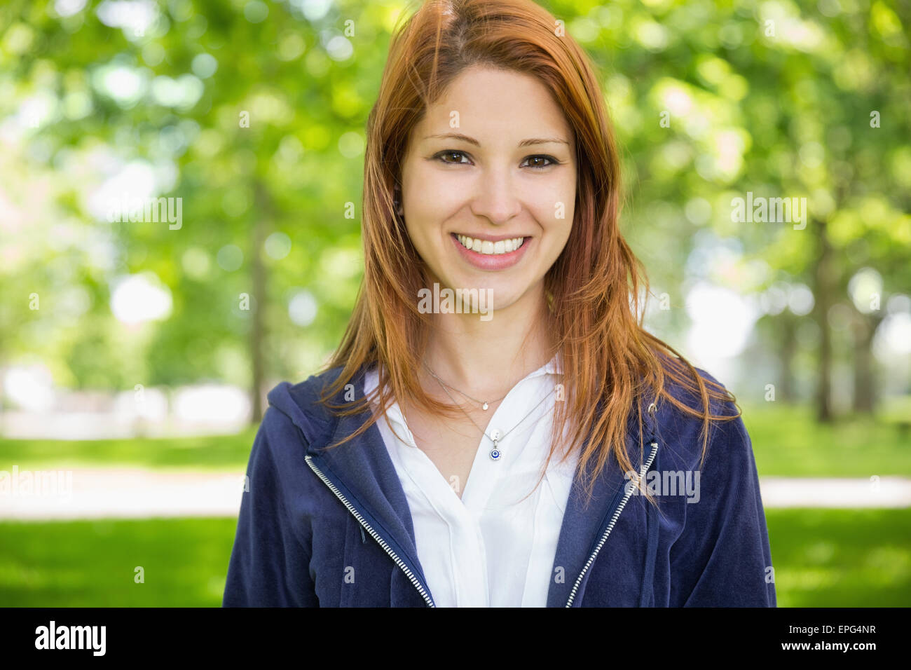 Pretty redhead smiling at camera in the park Stock Photo - Alamy