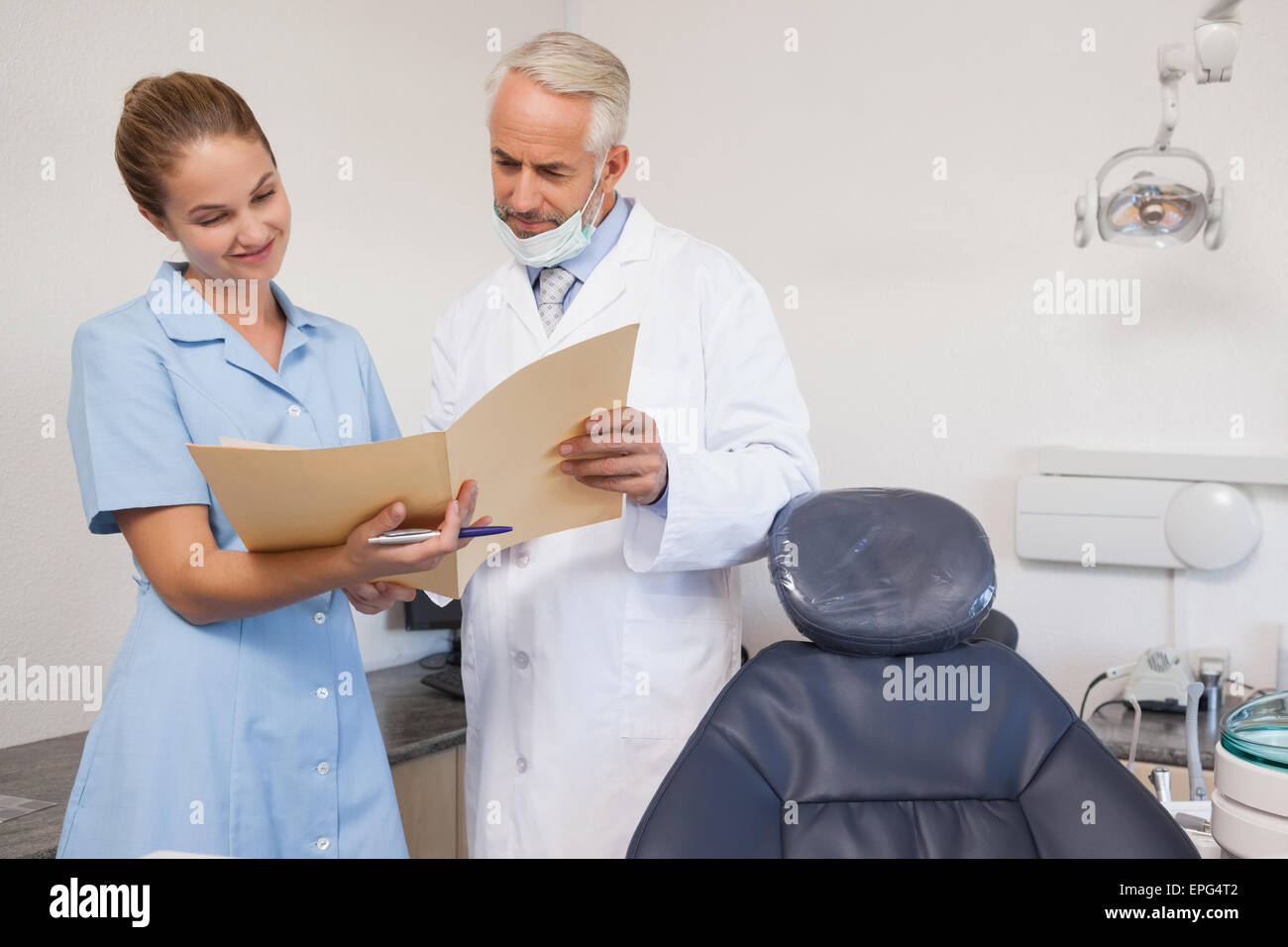 Dentist and assistant looking at file together Stock Photo - Alamy