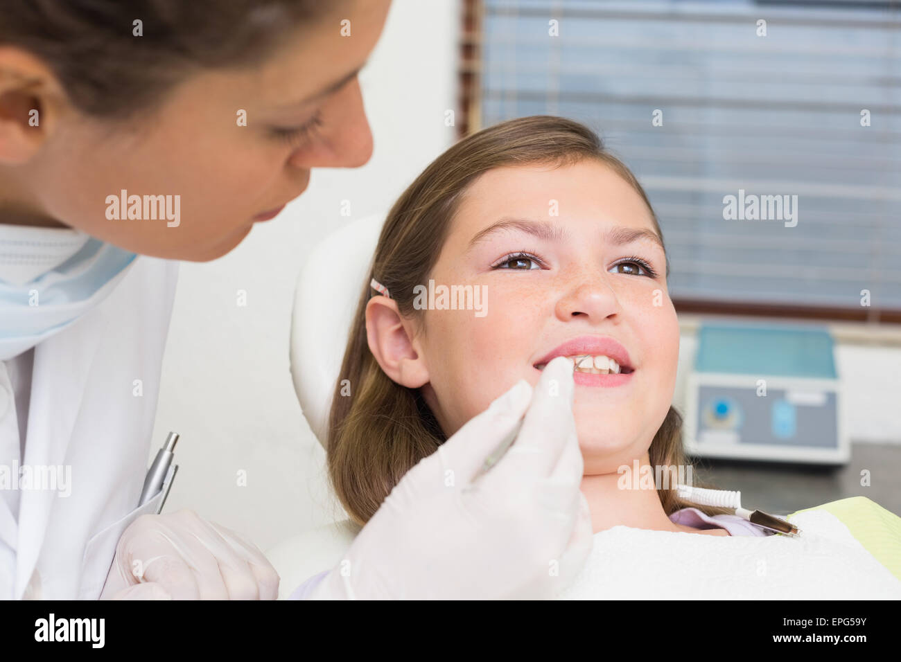 Pediatric dentist examining little girls teeth in the dentists chair ...