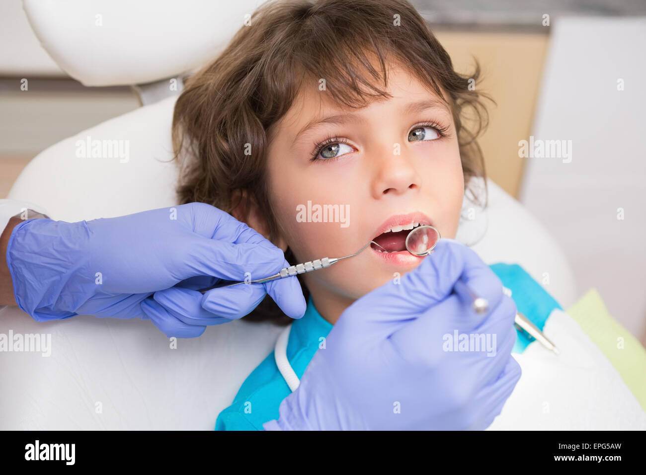 Pediatric dentist examining a little boys teeth in the dentists chair ...