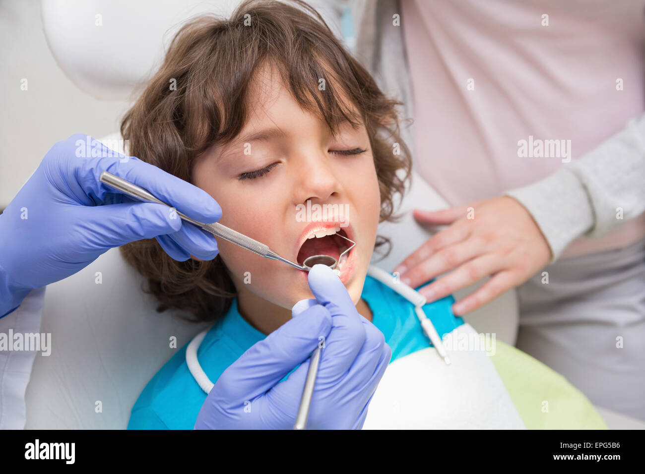 Pediatric dentist examining a little boys teeth with his mother Stock ...