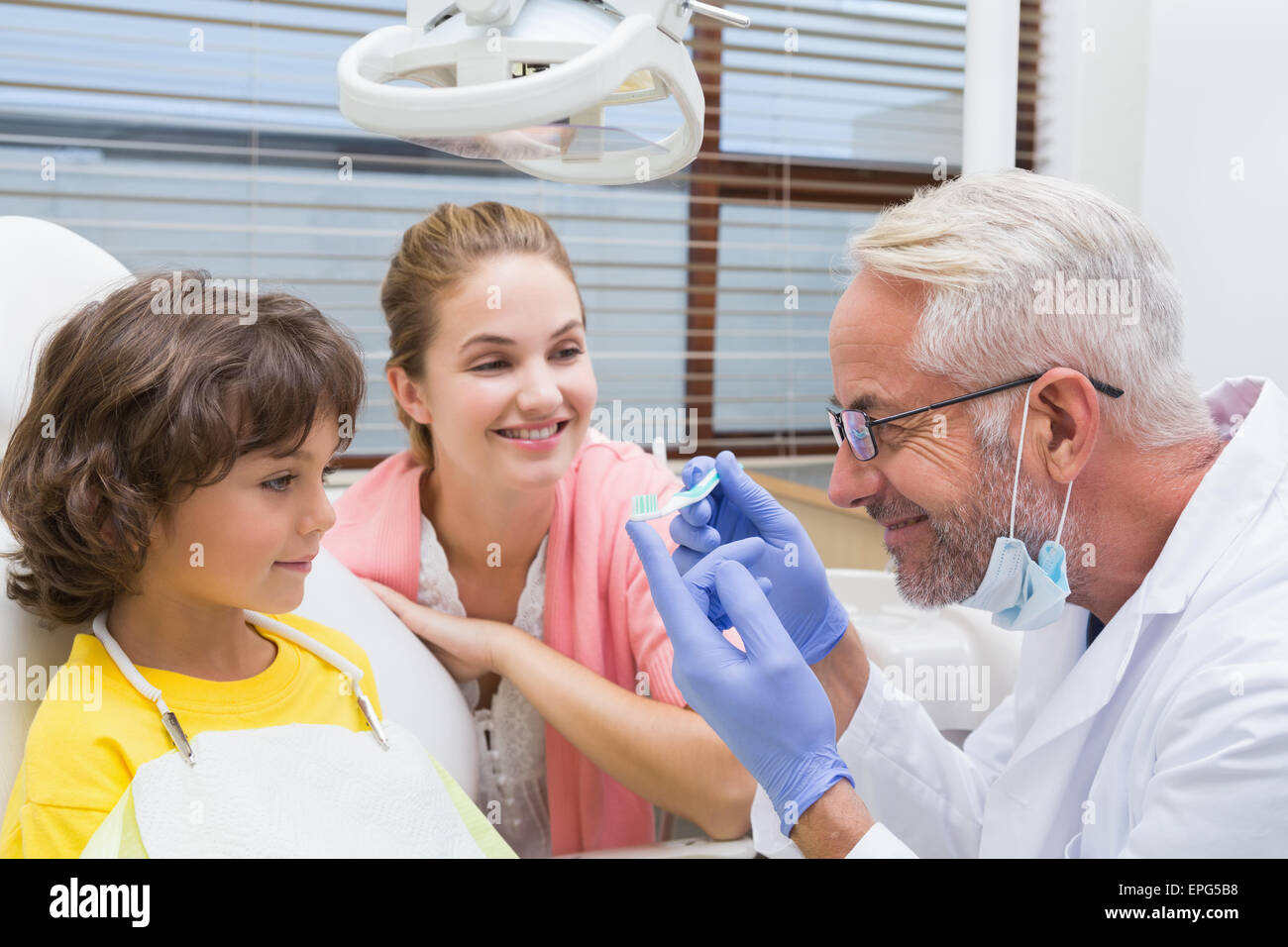 Pediatric dentist showing little boy a toothbrush with his mother Stock ...
