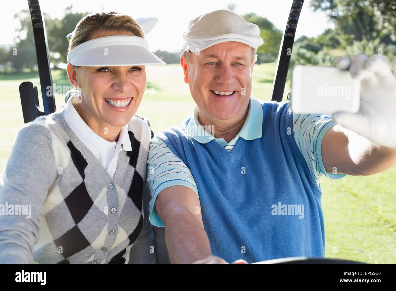 Happy golfing couple sitting in golf buggy taking a selfie Stock Photo ...