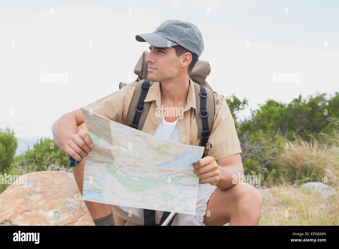 Hiking man sitting with map on mountain terrain Stock Photo - Alamy