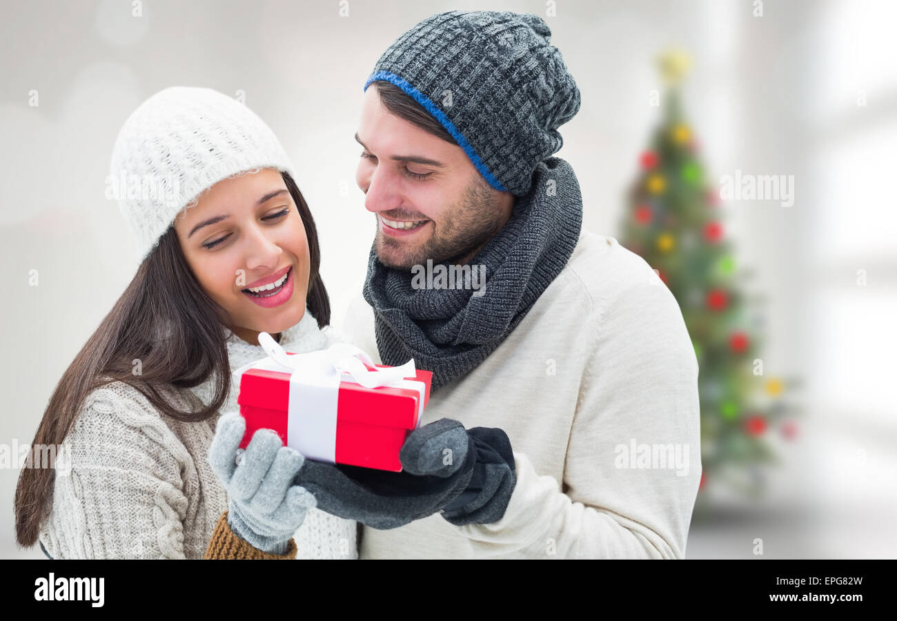 Composite image of winter couple holding gift Stock Photo - Alamy