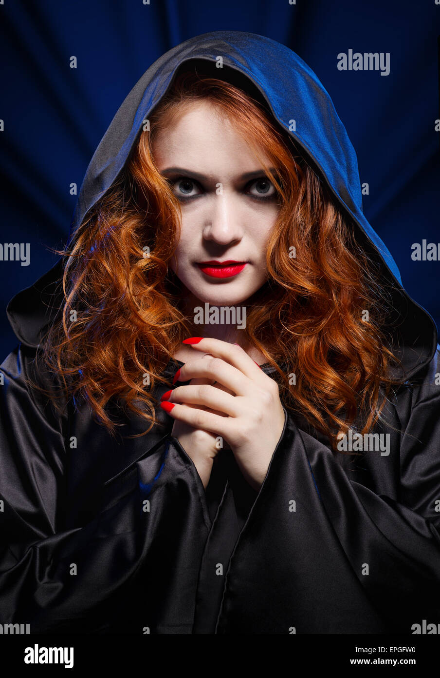 Young witch on blue light background Stock Photo - Alamy