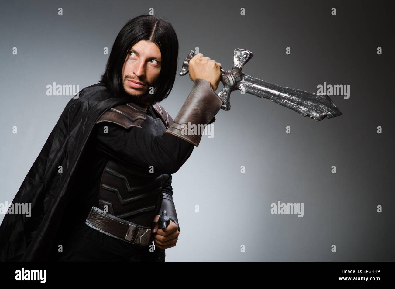 Angry knight with sword against dark background Stock Photo - Alamy