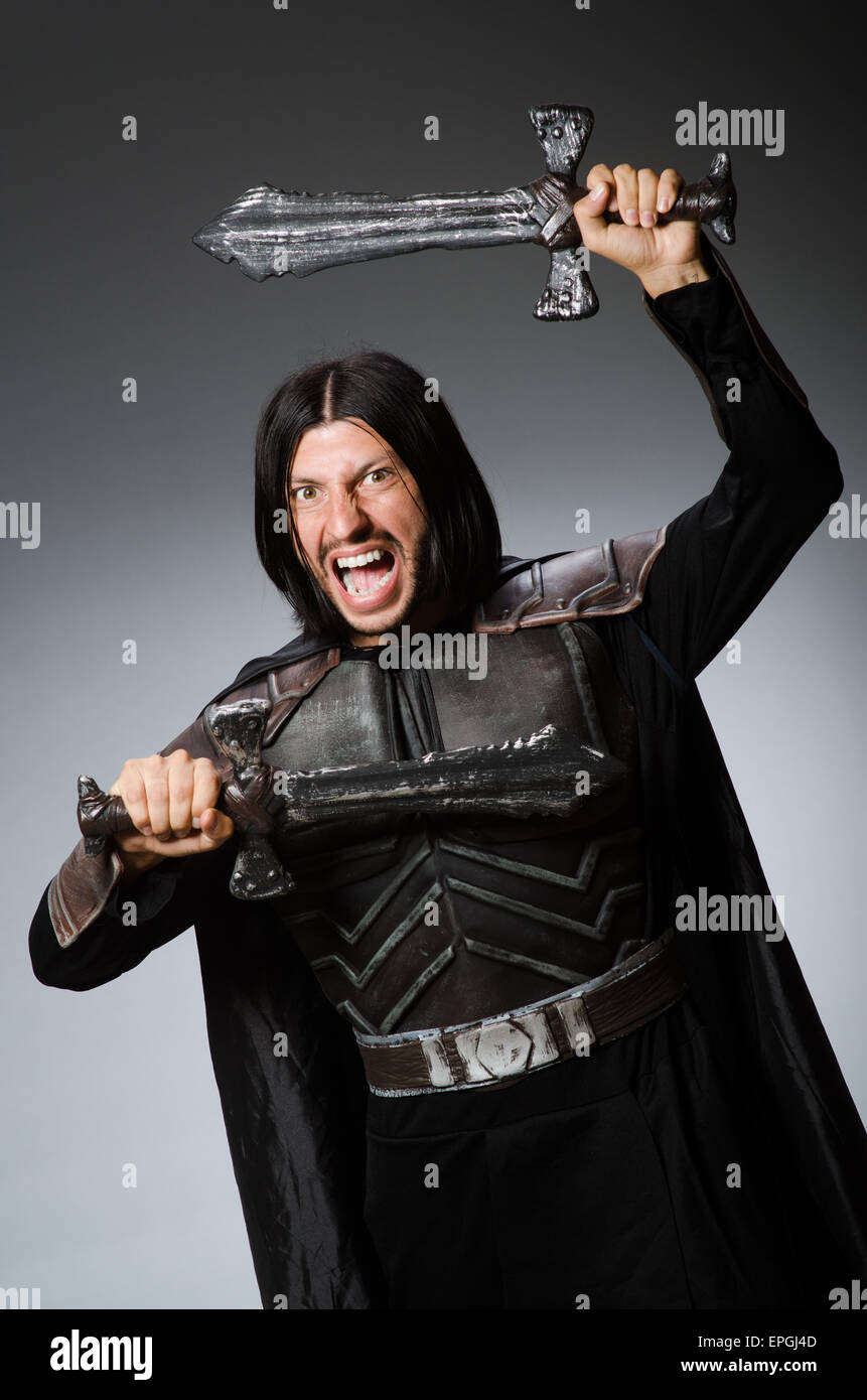 Angry knight with sword against dark background Stock Photo - Alamy
