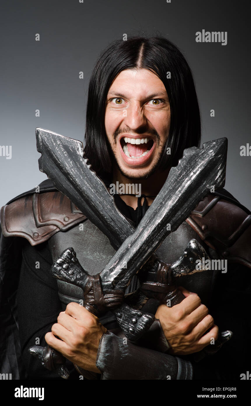 Angry knight with sword against dark background Stock Photo - Alamy