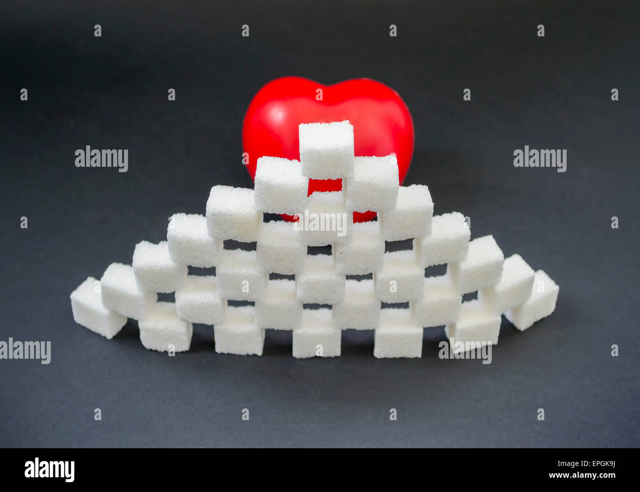Heart shape trapped behind a wall made of white sugar cubes, concept ...