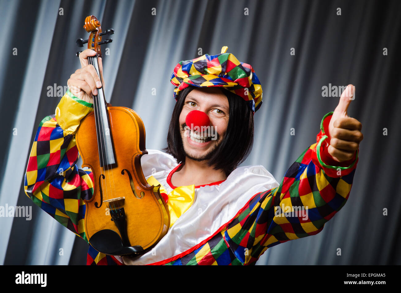 Funny clown plyaing violin against curtain Stock Photo - Alamy