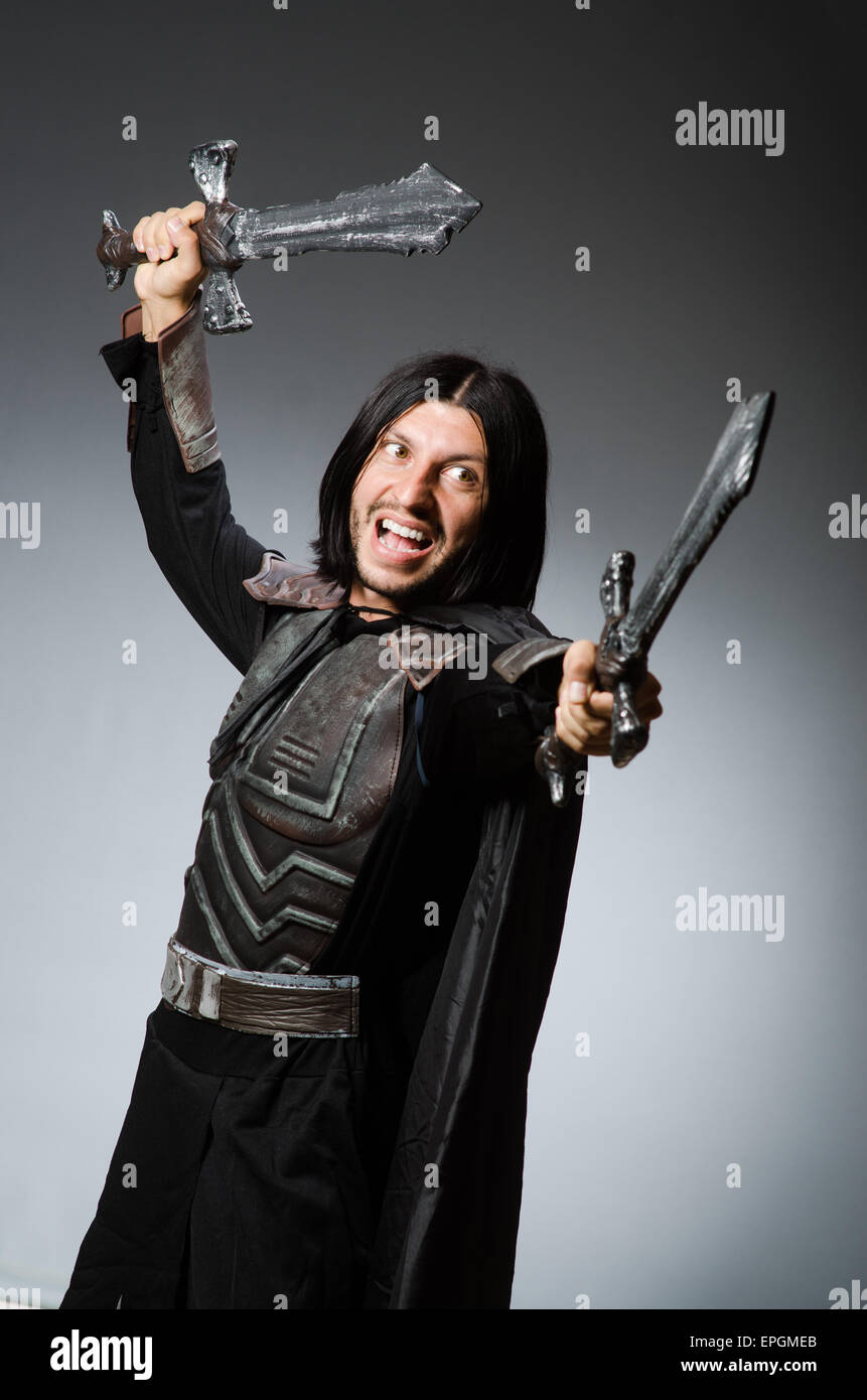 Angry knight with sword against dark background Stock Photo - Alamy